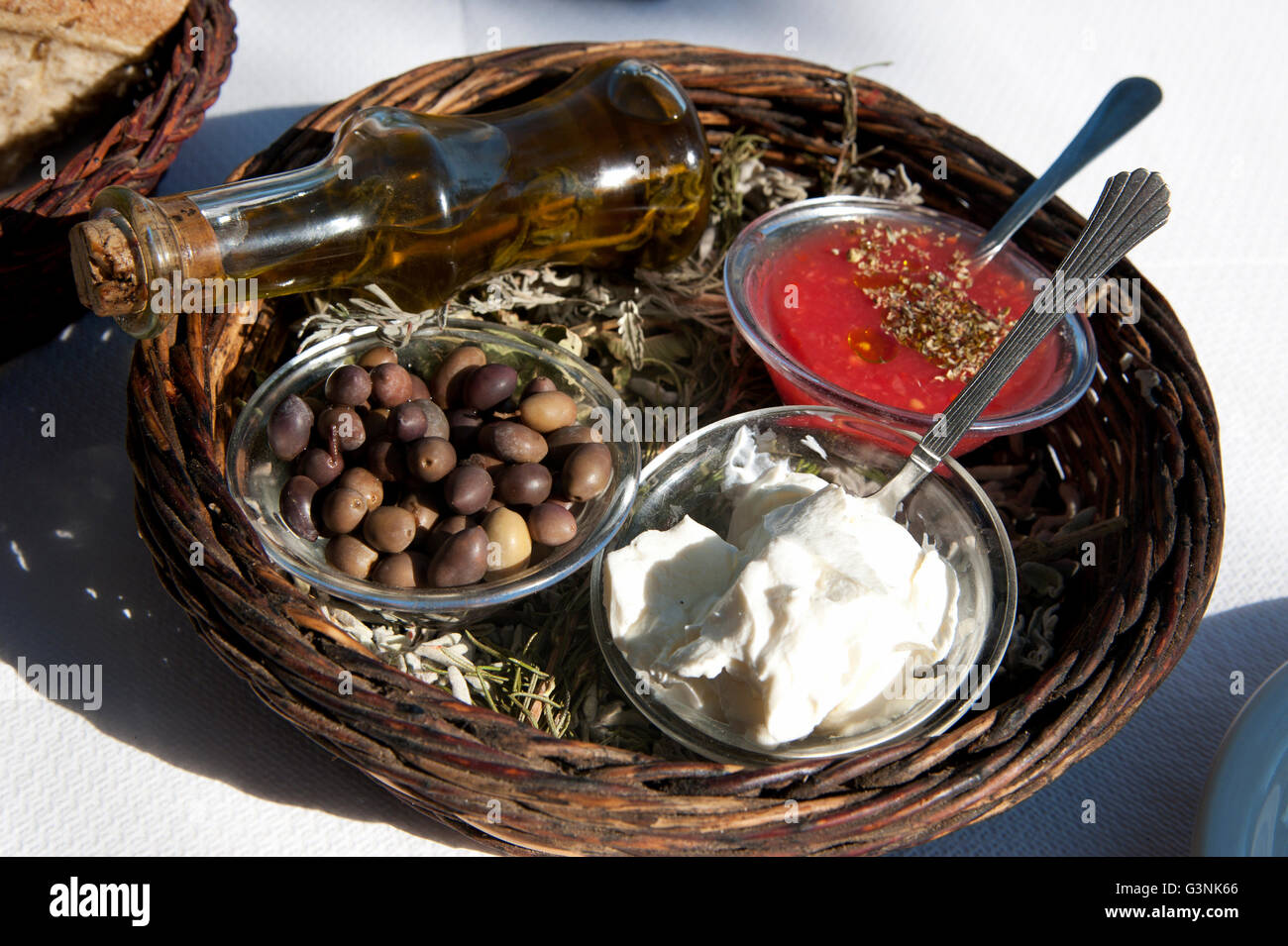 A wicker basket with olive oil, olives and dips at a tavern, Crete ...