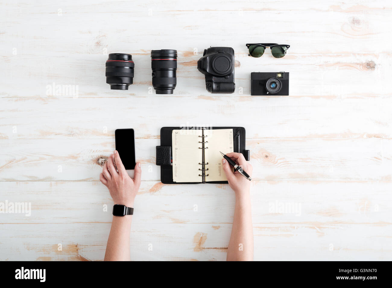 Hands of young man writing in notebook and using blank screen mobile ...