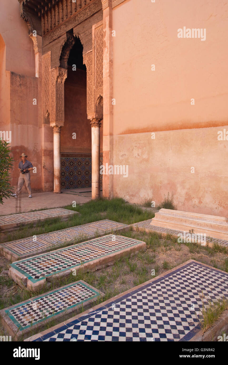 Tourist walks past tiled tombs outdoors at Saadien Tombs, Marrakech ...
