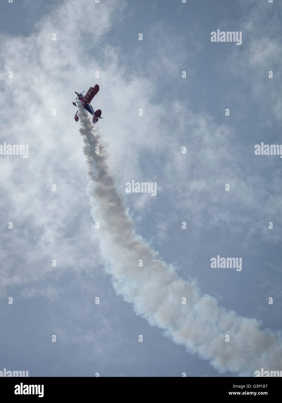 Pitts Special acrobatic airplane in the sky with long white smoke trail ...