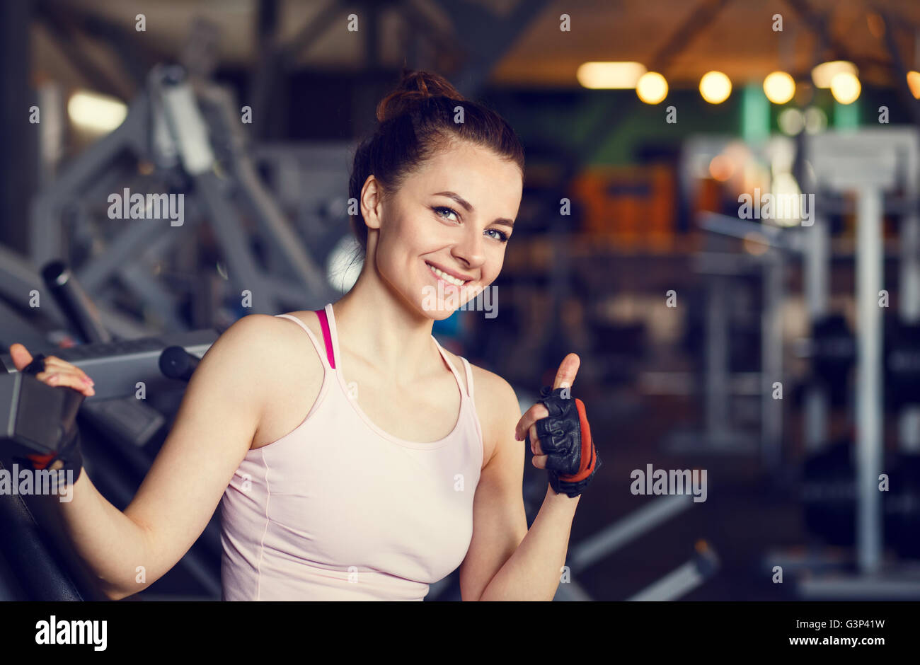 Young smiling woman in a fitness center. Happy beautiful girl in a gym ...