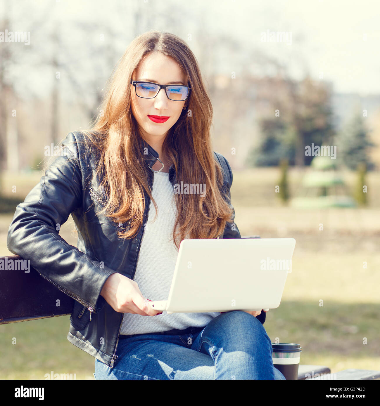 Young Businesswoman Using Laptop Sitting On Bench In The Park European