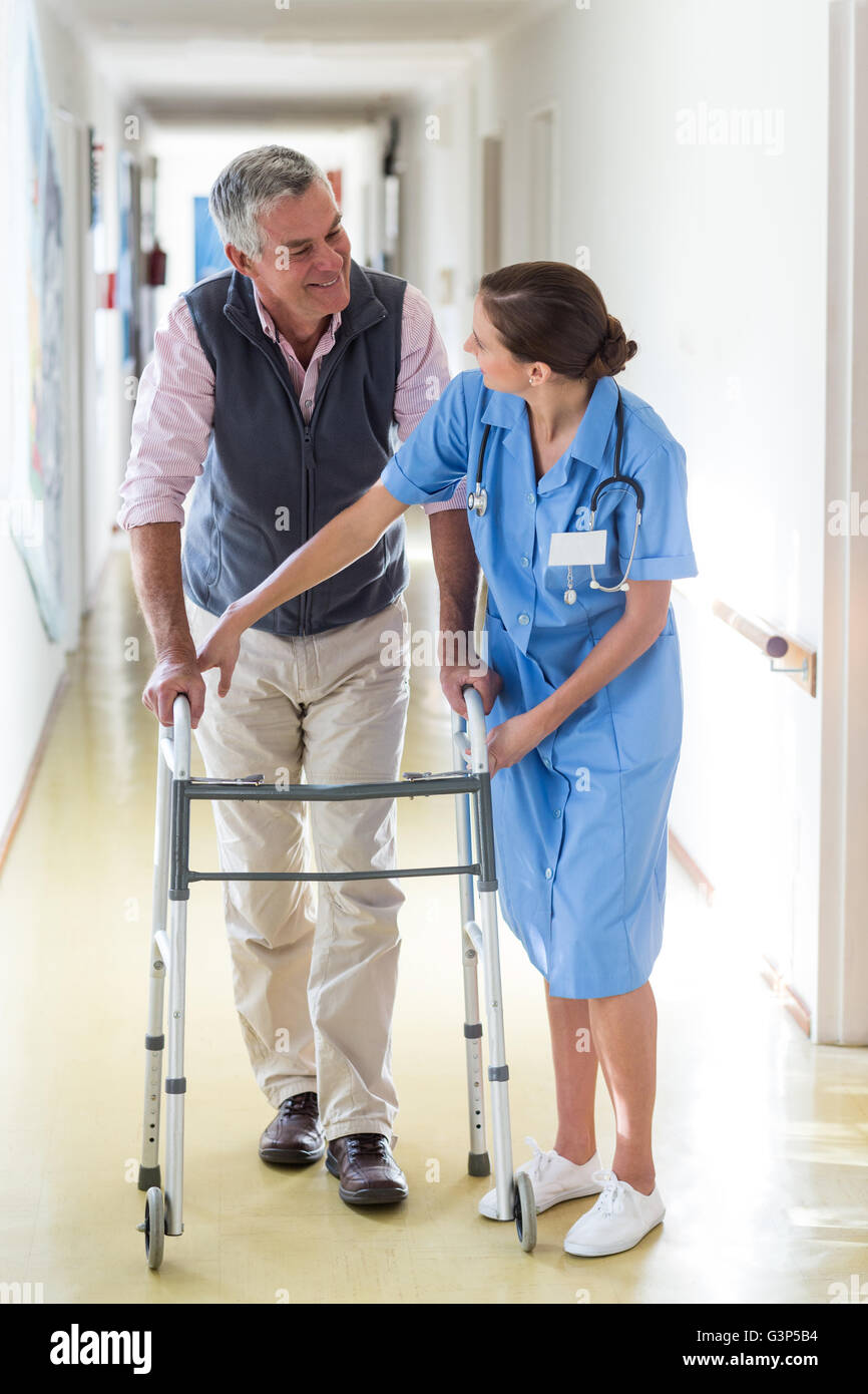 Nurse helping senior patient to walk with walking frame Stock Photo - Alamy