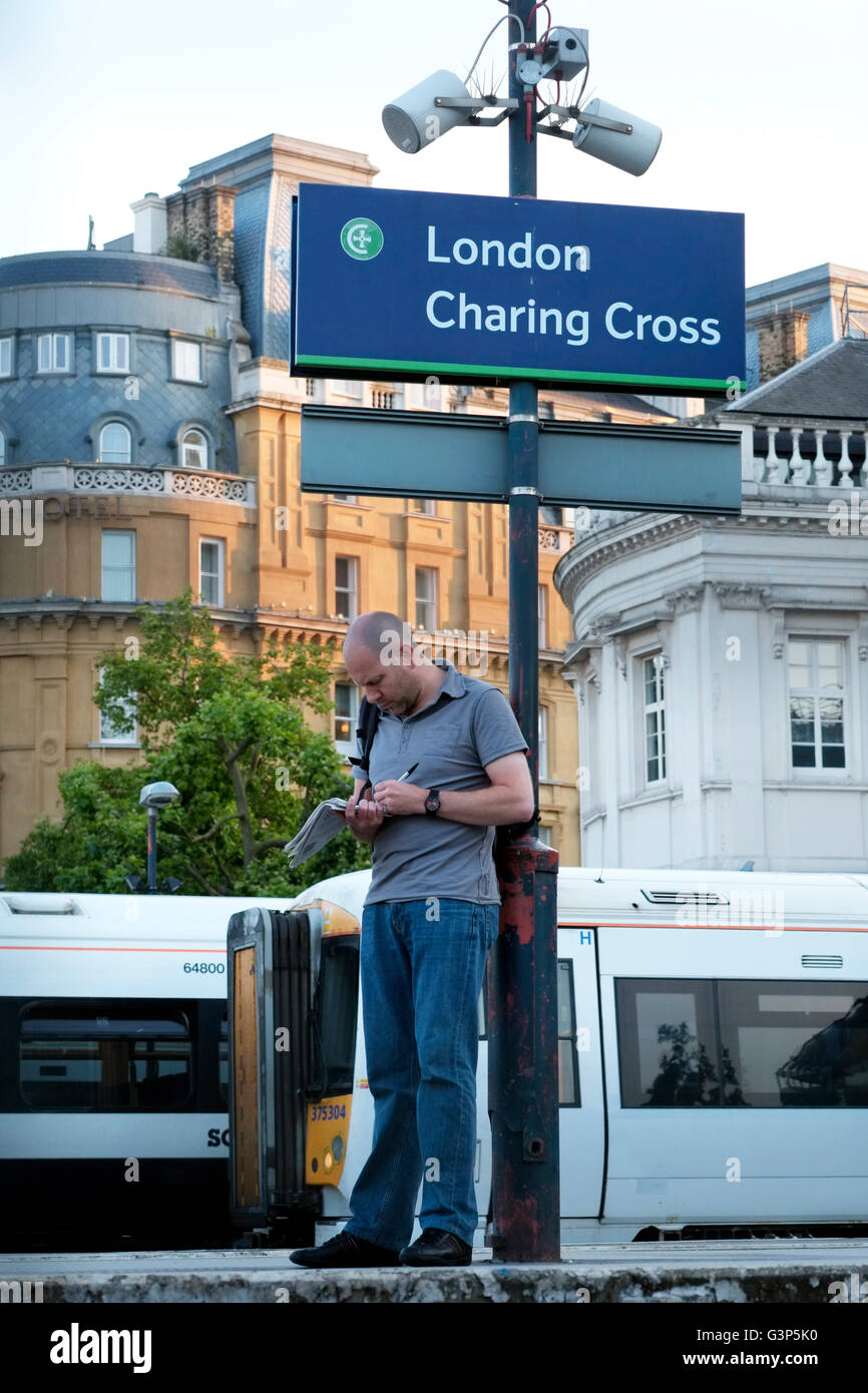 Commuter doing crossword puzzle at Charing Cross Station London Stock ...