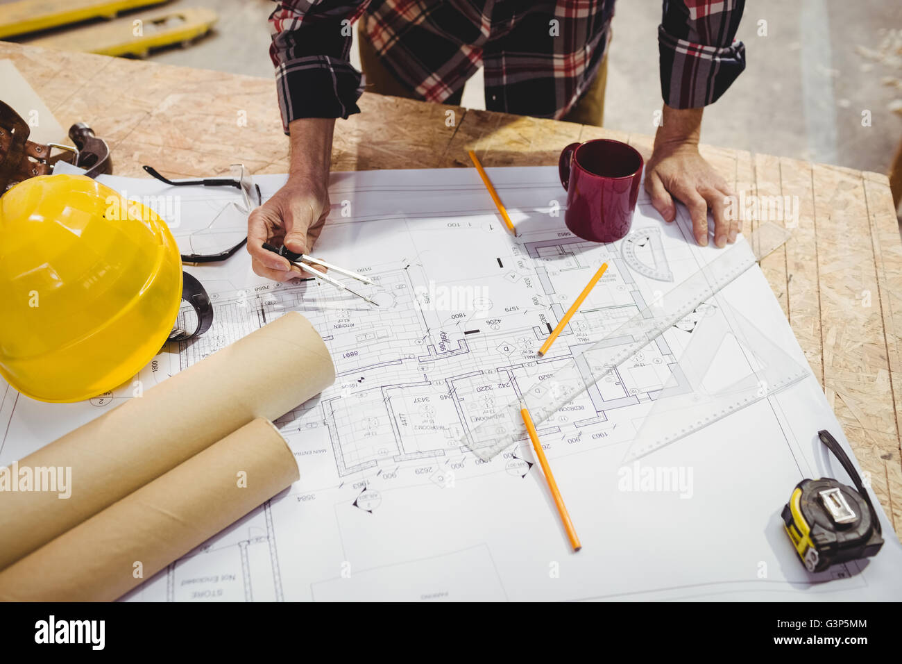 Carpenter drawing on a plan with a compass Stock Photo - Alamy