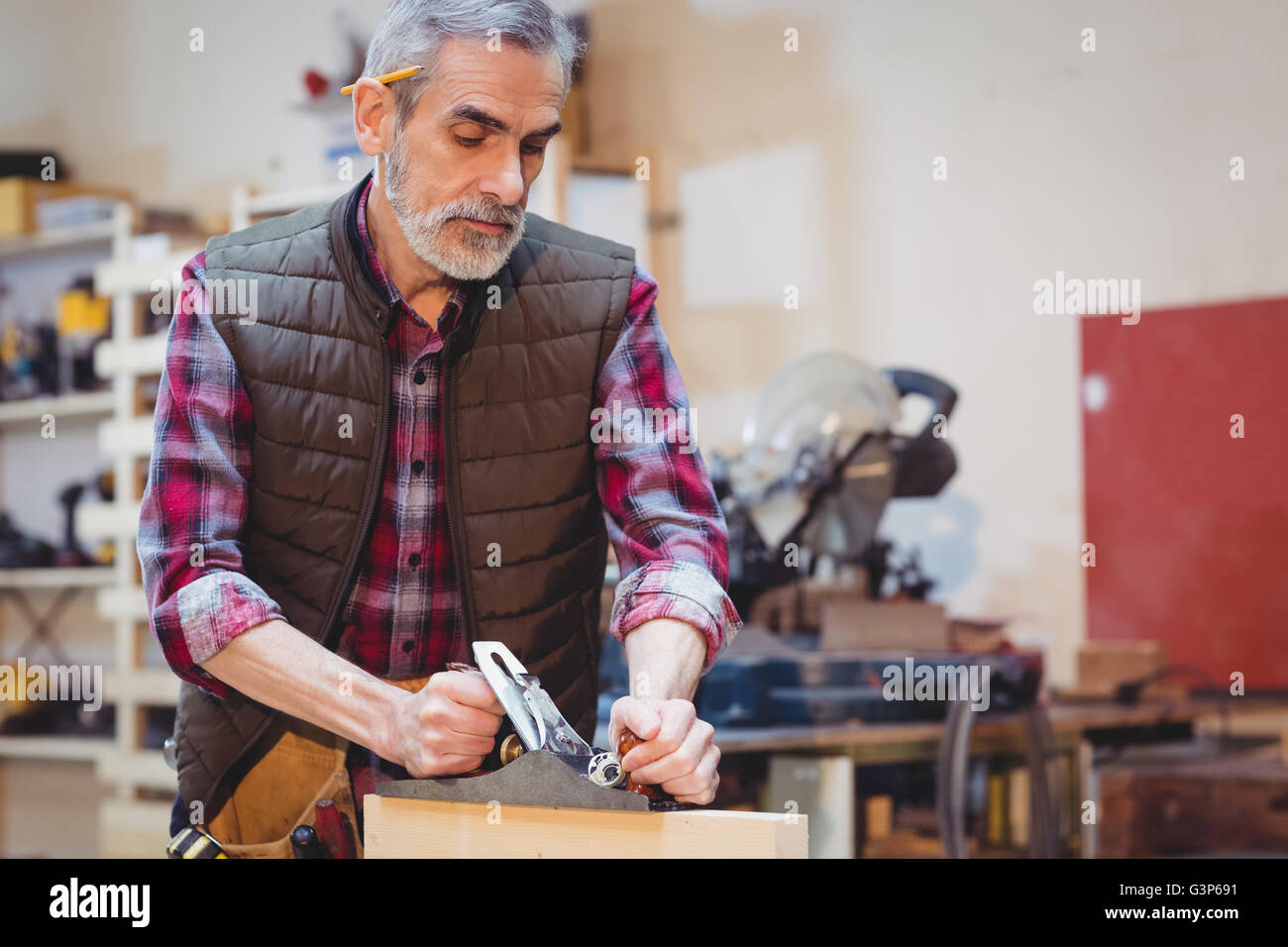 Portrait of carpenter perfecting wood plank form with a work tool Stock ...