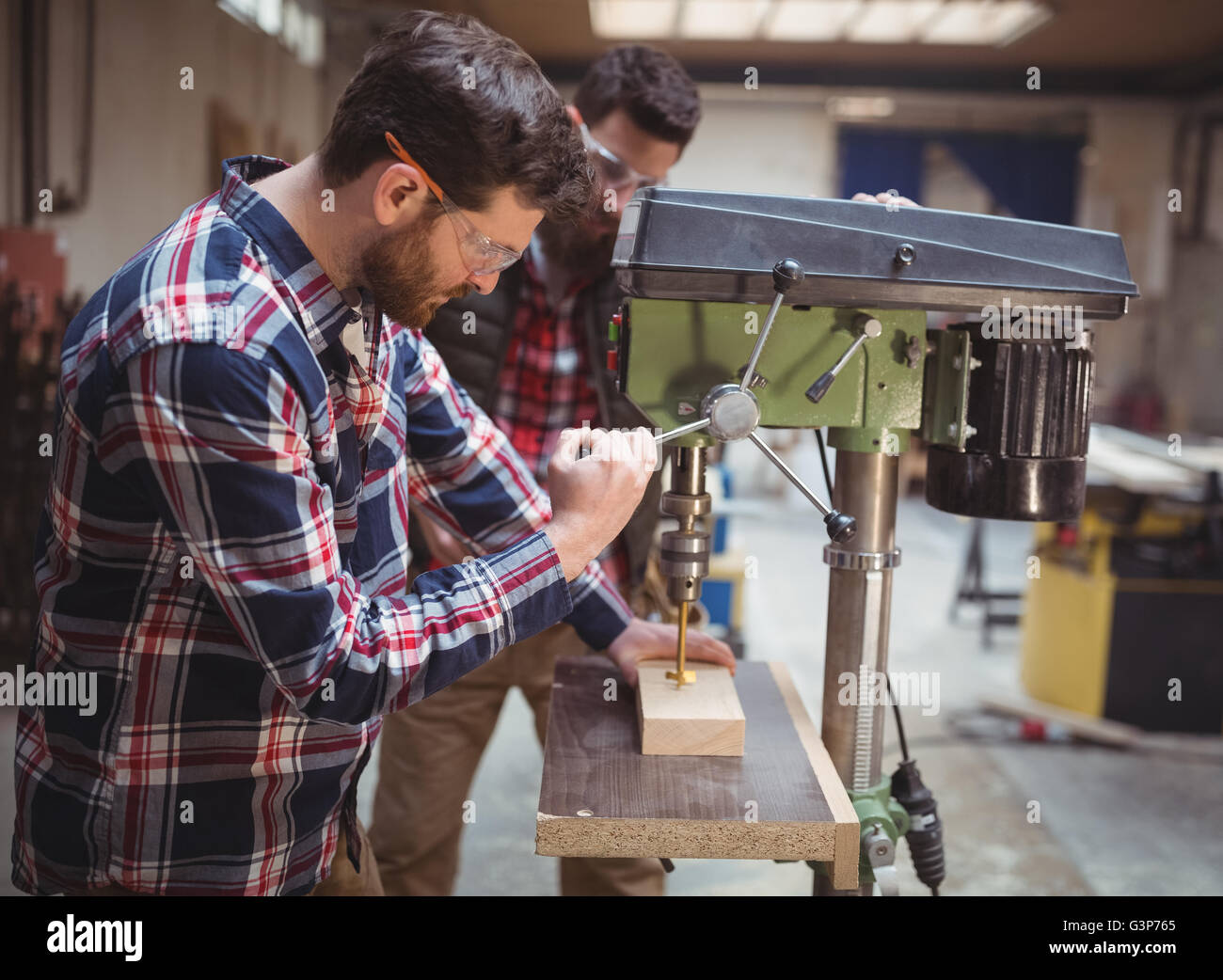 Carpenter working on a drill press machine Stock Photo - Alamy