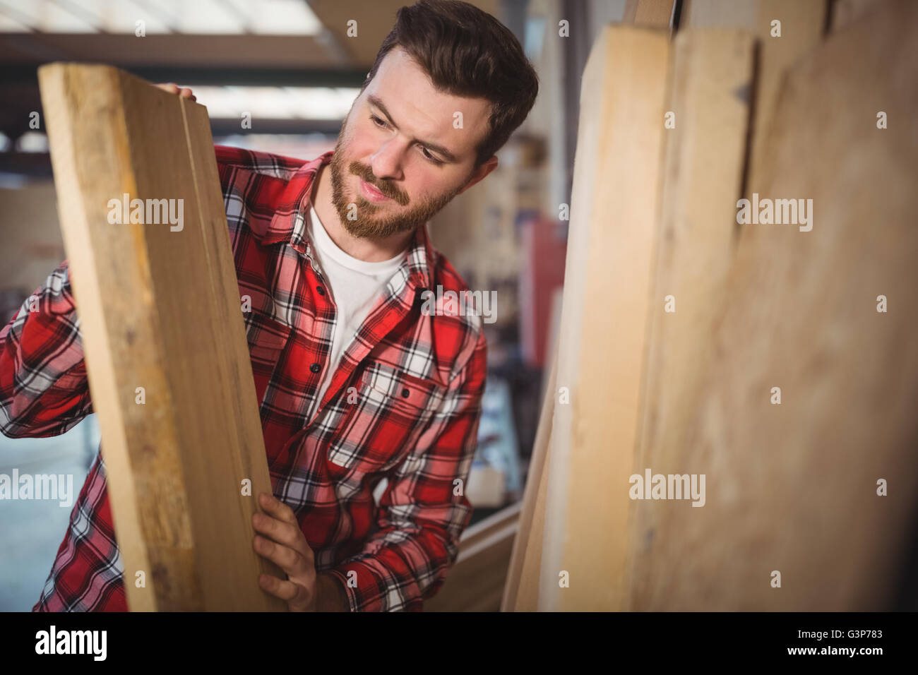 Carpenter looking at wooden plank Stock Photo - Alamy