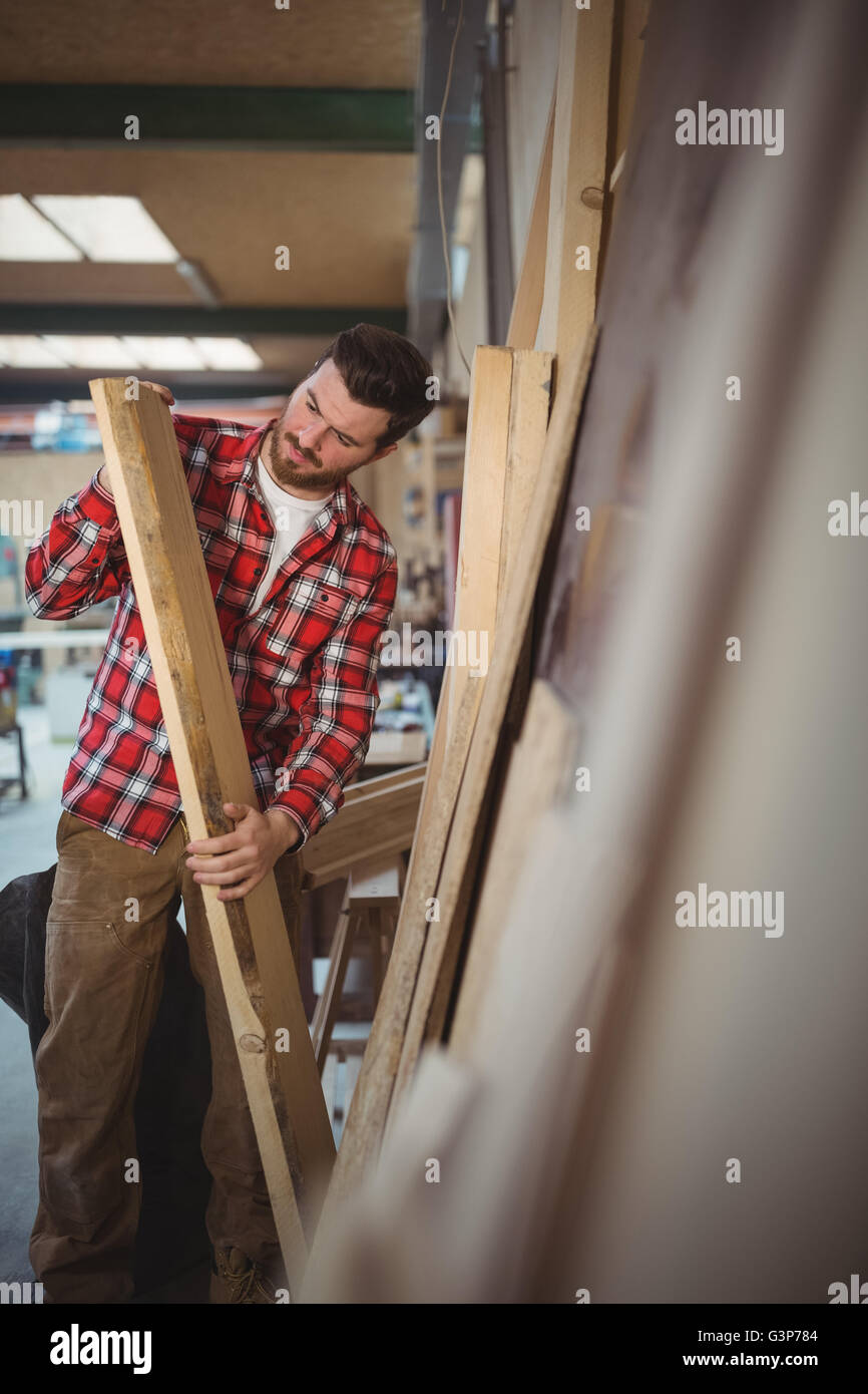 Carpenter looking at wooden plank Stock Photo - Alamy