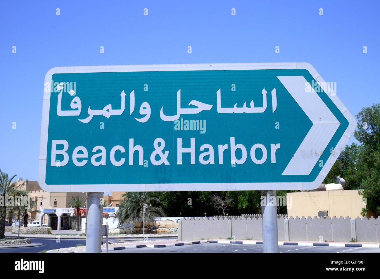 Road sign indicating Beach and Harbor in English and Arabic in the ...