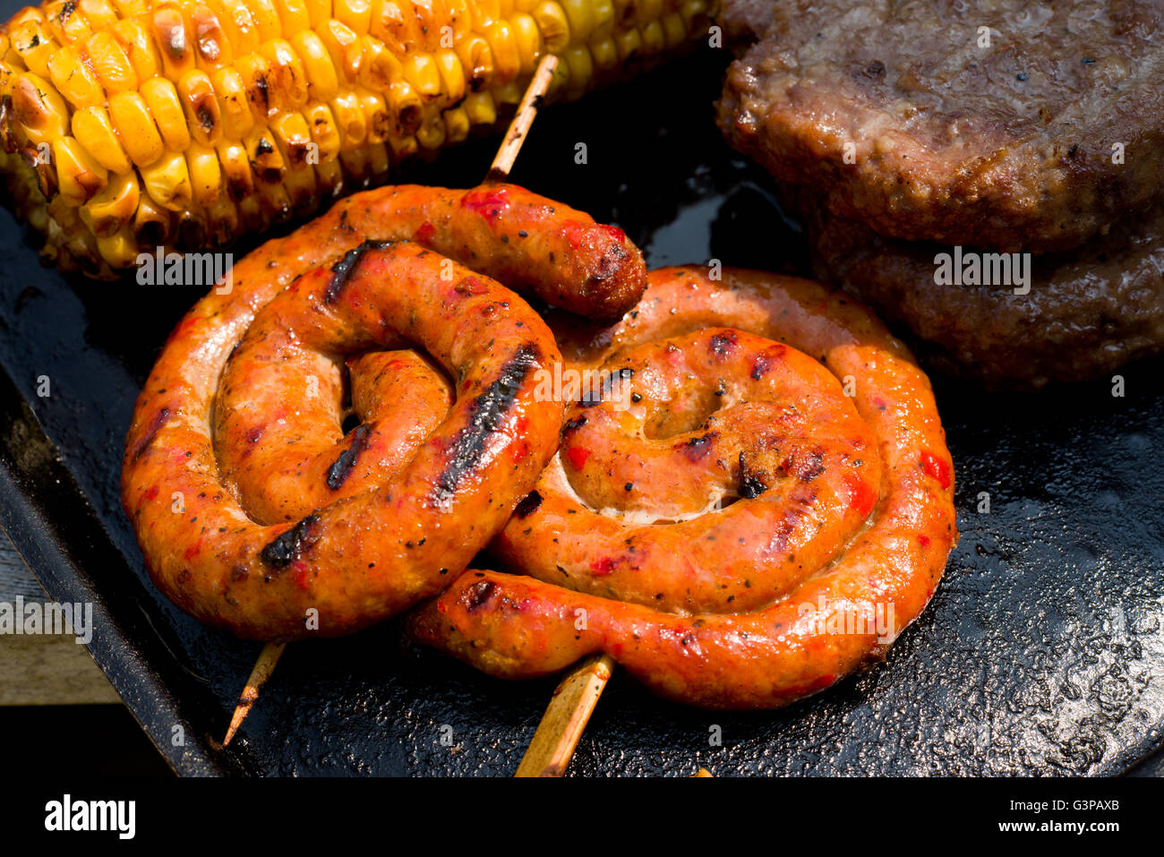 Circular coiled sausages on a barbeque. Spiral of sausage with a wooden ...