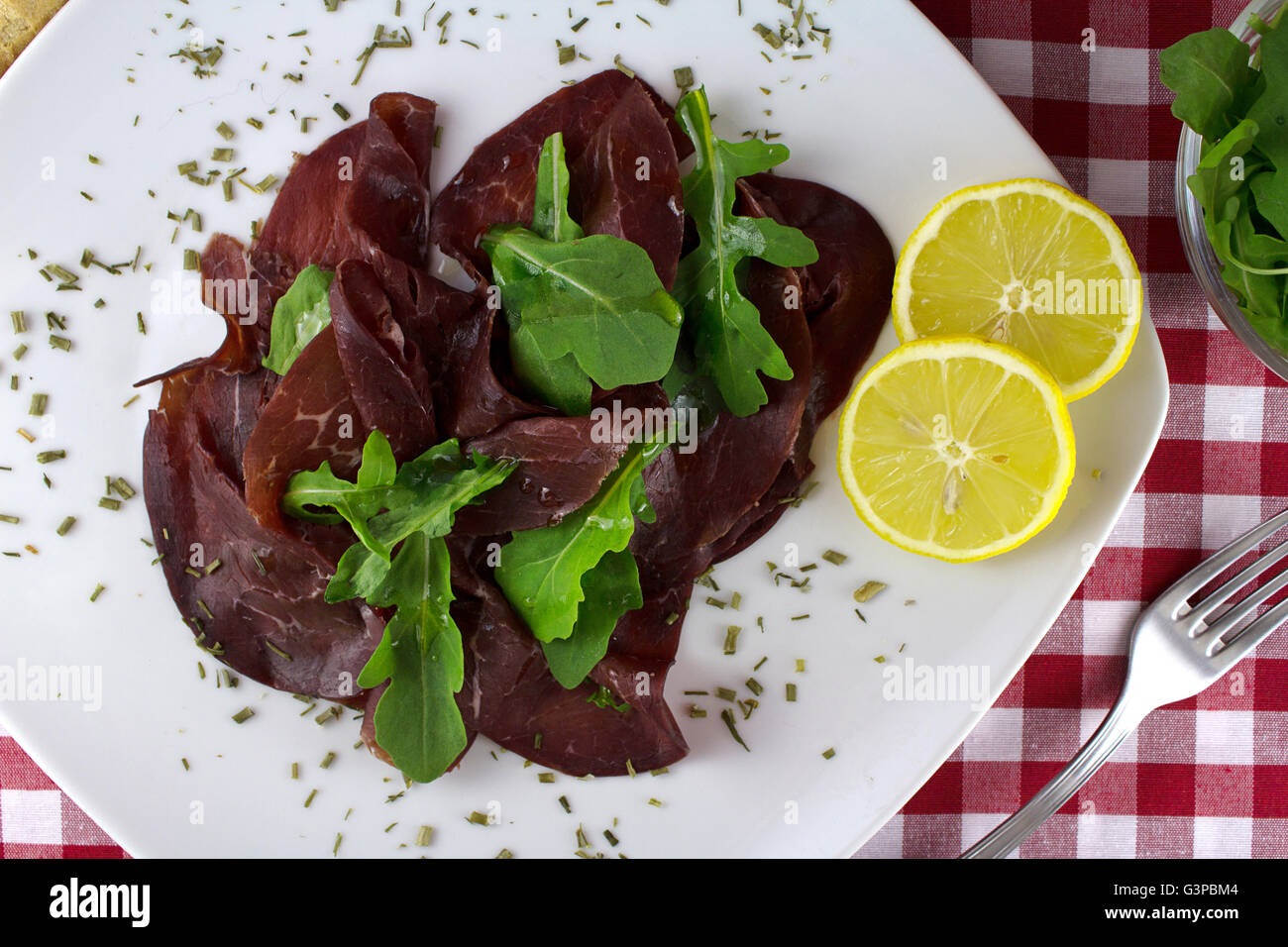Slices of air-dried beef, called as bresaola, with rucola salad, olive ...