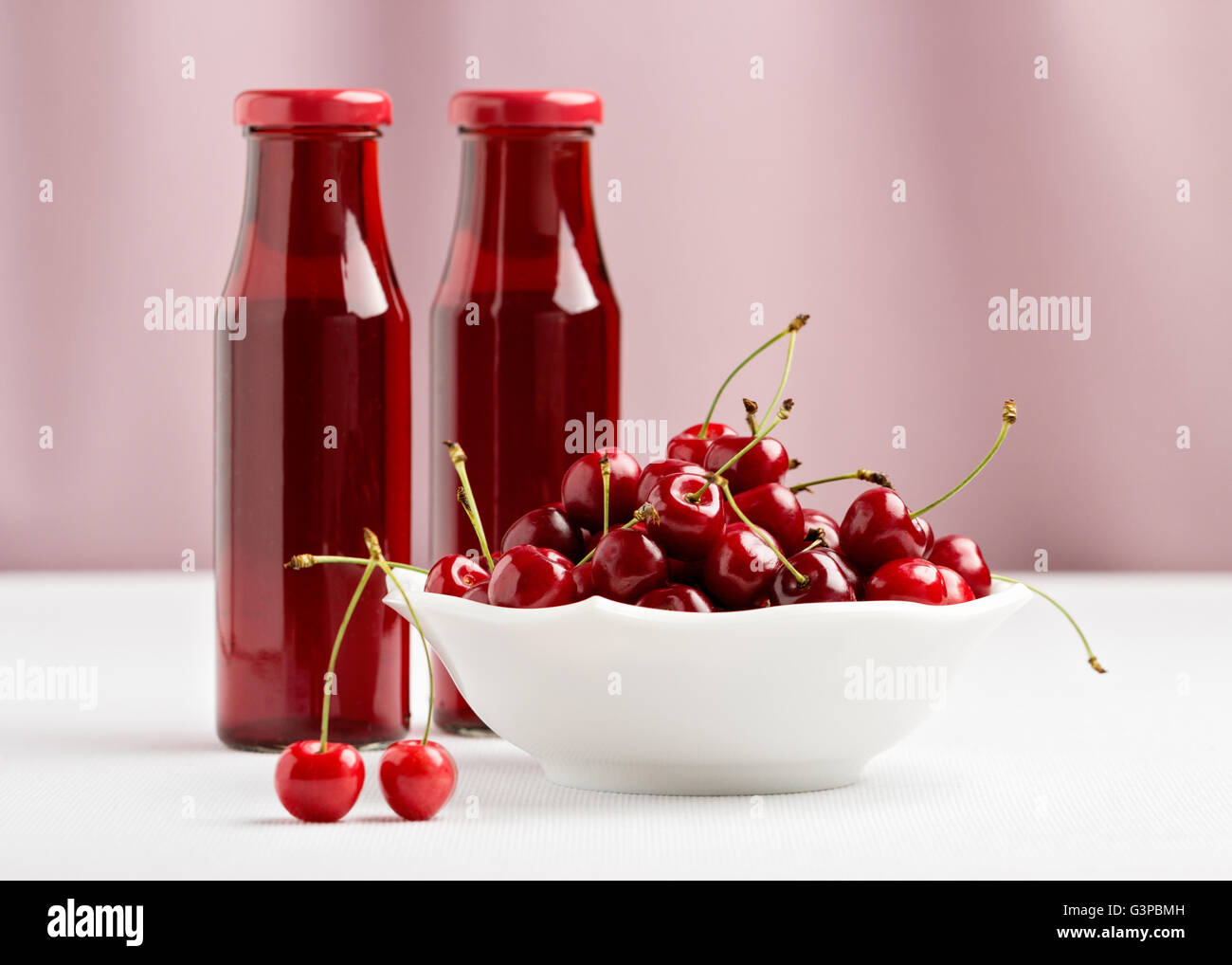Cherries in a bowl and two bottles of cherry juice. Selective focus ...