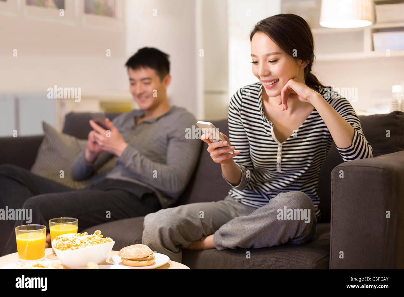 Young couple using smart phones on living room sofa Stock Photo - Alamy
