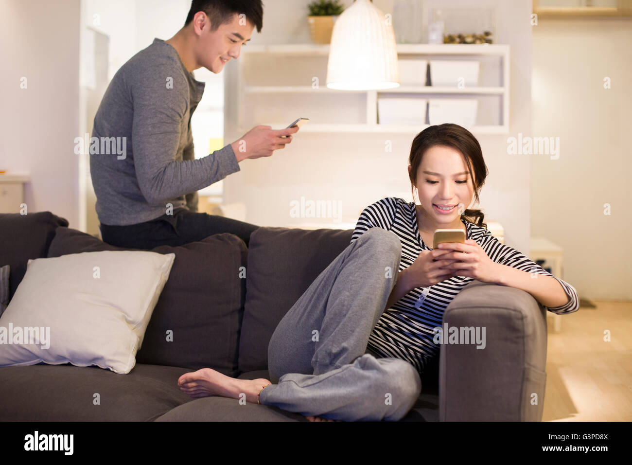 Young couple using smart phones on living room sofa Stock Photo - Alamy