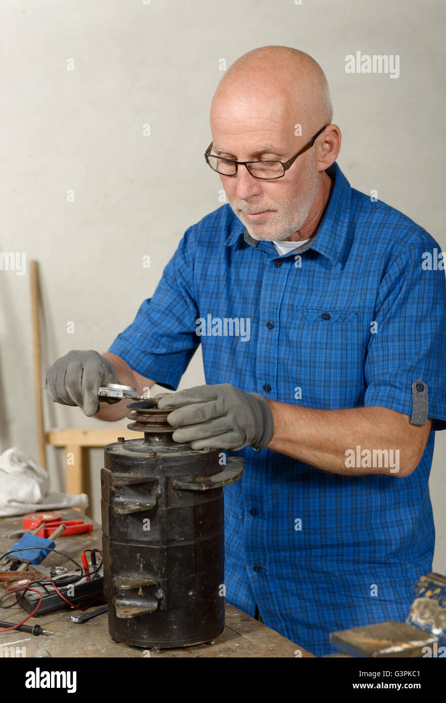 a man with antique car generator in his workshop Stock Photo - Alamy
