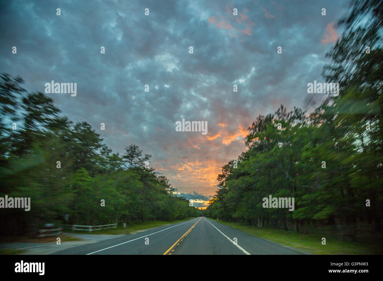 brilliant sunset in the distance while on a two lane highway in East ...
