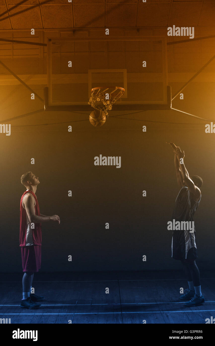 Two basketball player in a gymnasium with one scoring a shoot Stock ...