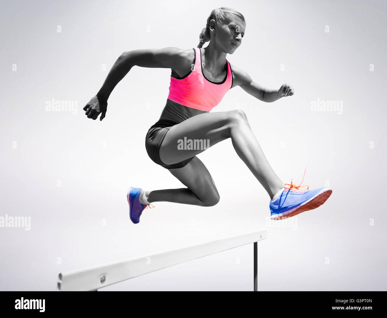 Sporty woman jumping a hurdle Stock Photo - Alamy