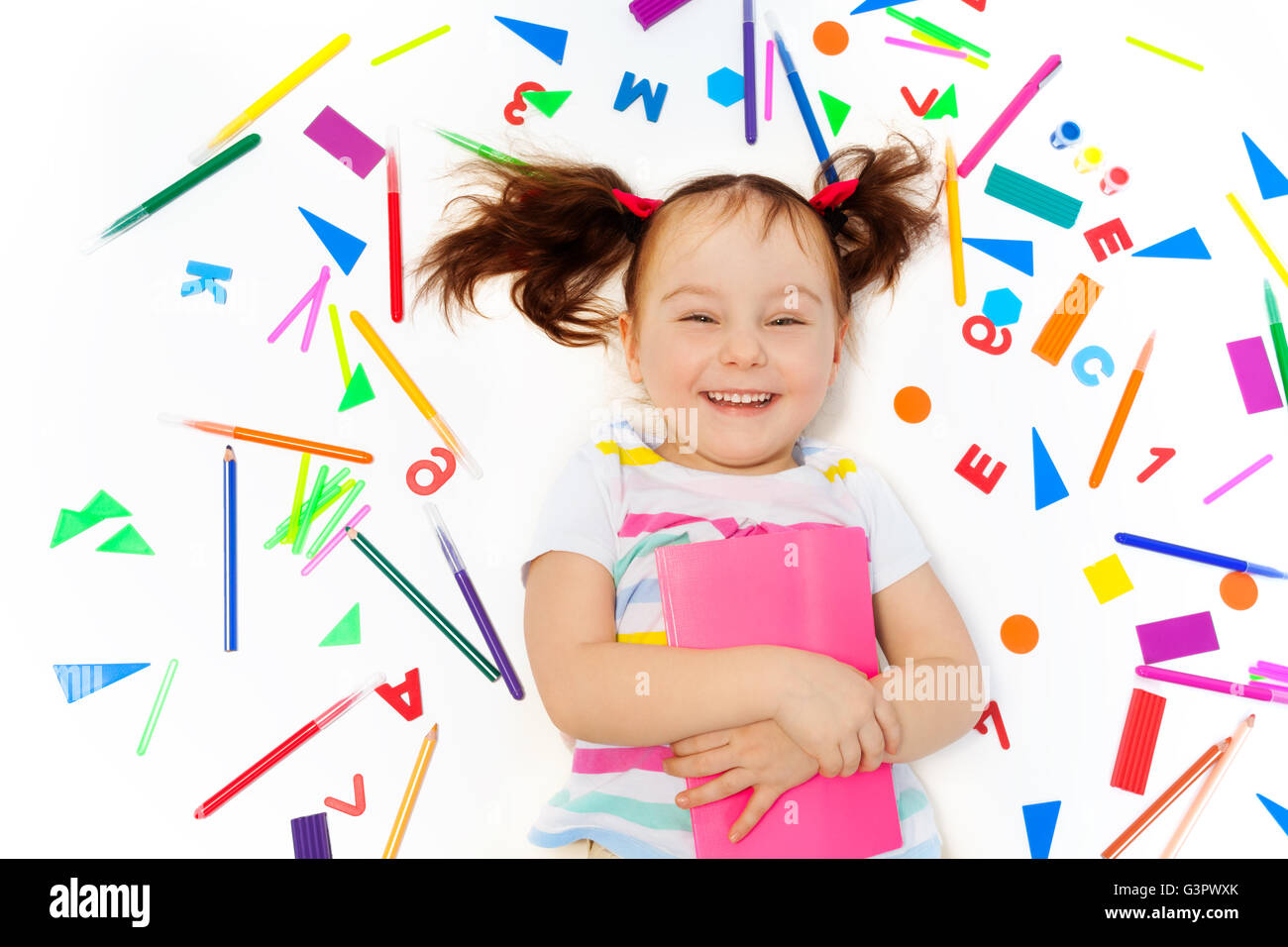Laughing preschool girl holding pink book Stock Photo - Alamy