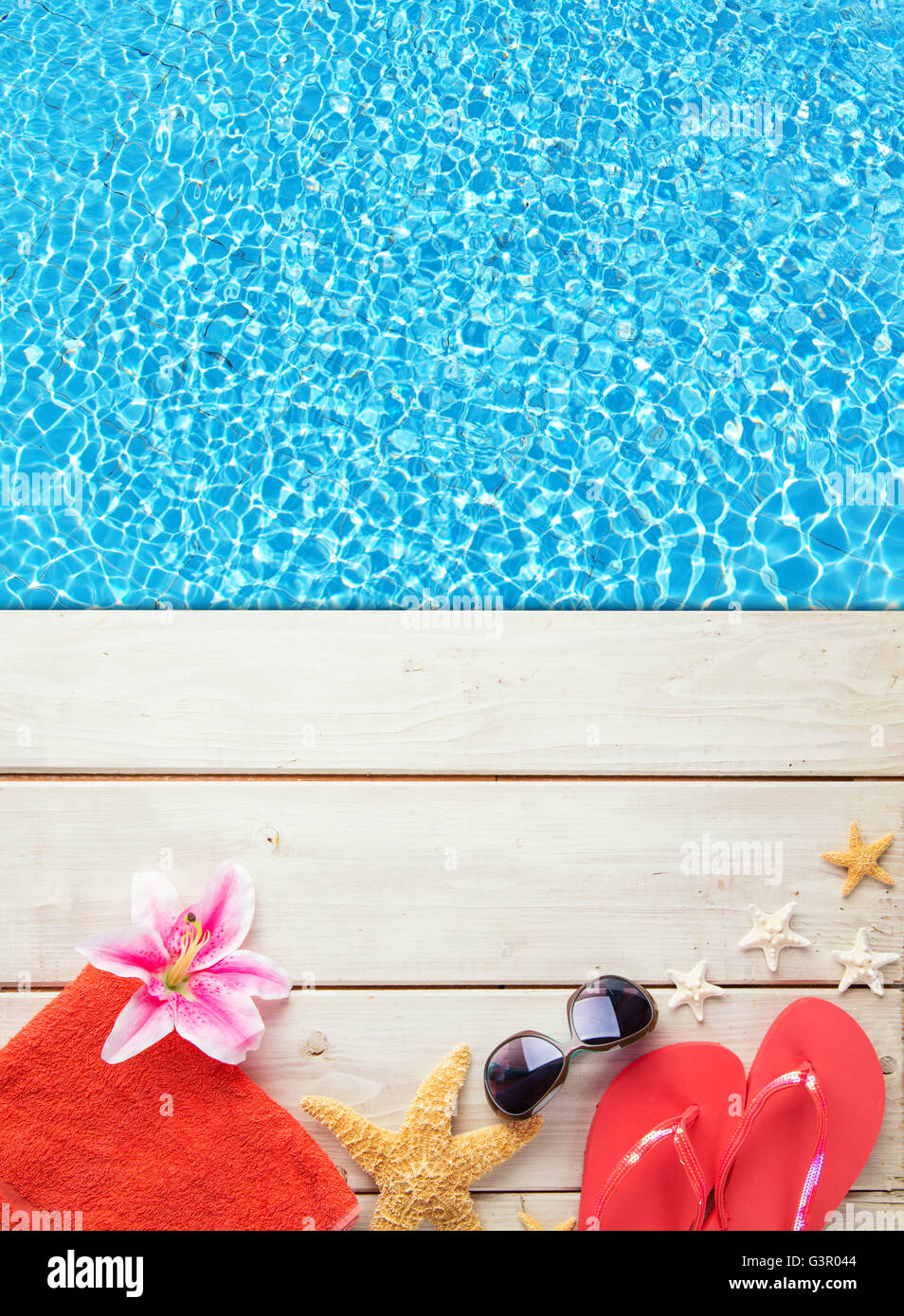 Beach accessories on wooden desk placed over swimming pool. Copyspace ...
