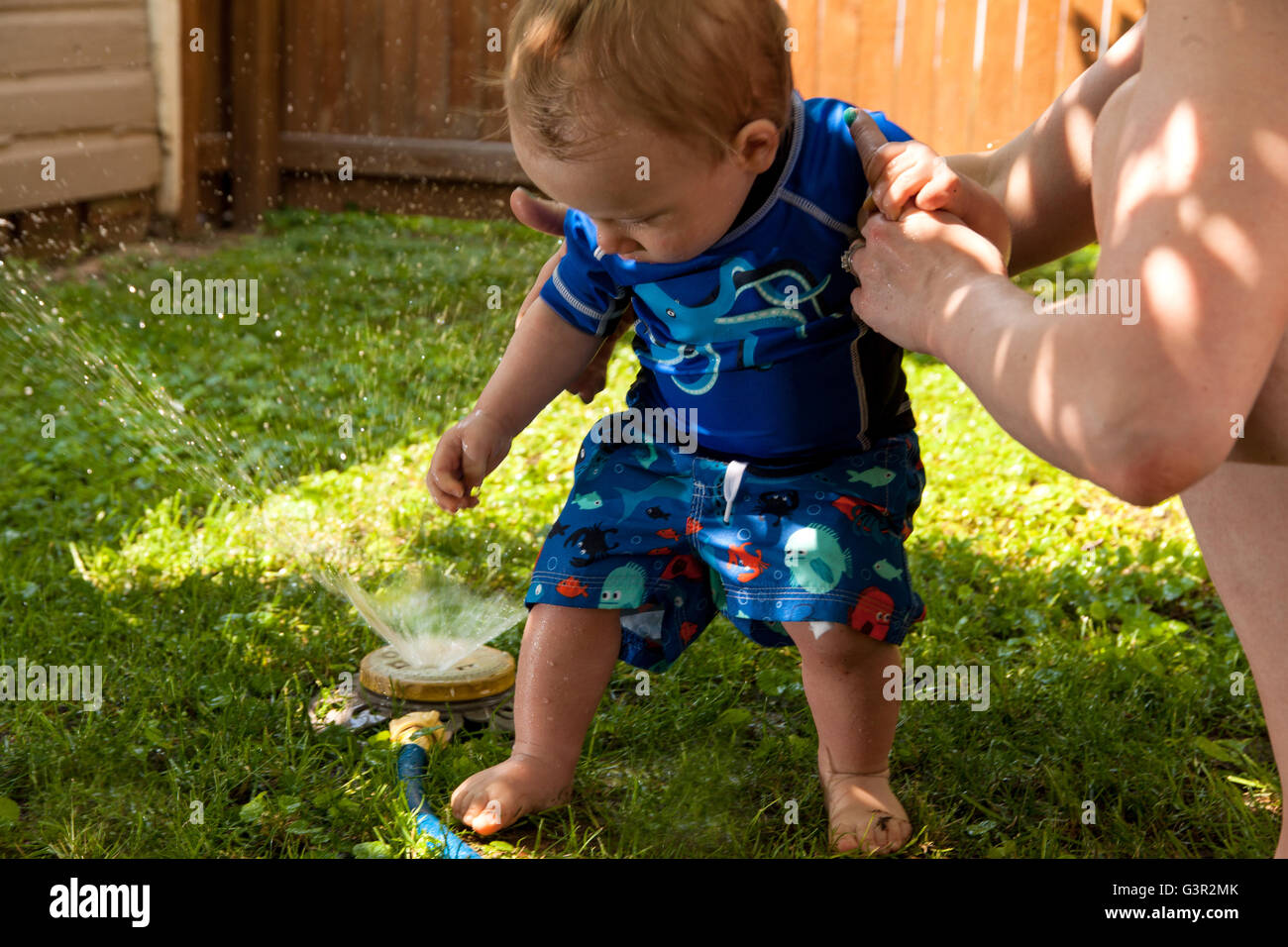 Baby Caucasian Boy and Mother playing in his backyard with a garden ...