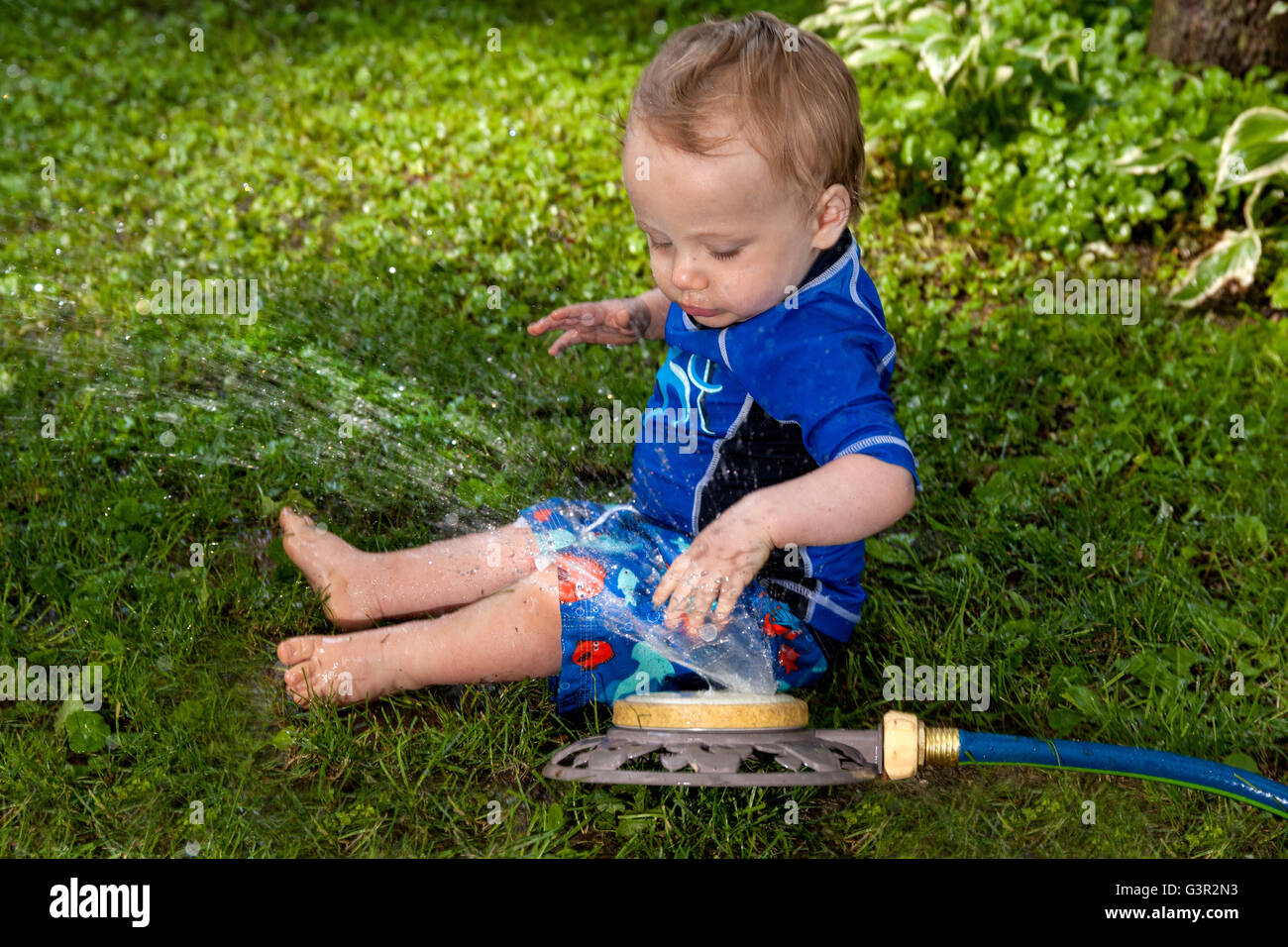Two kids playing water sprinkler hi-res stock photography and images ...