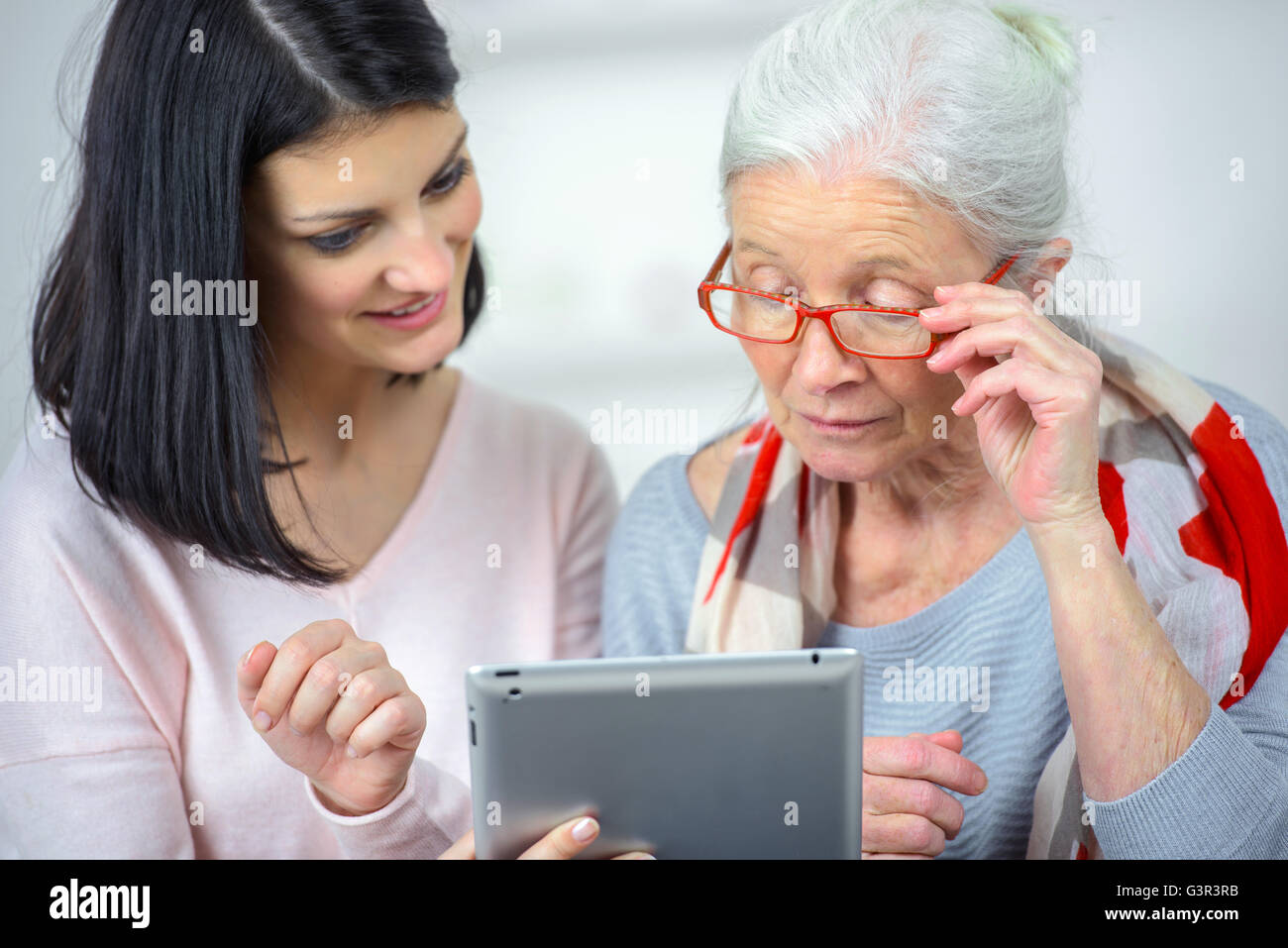 Helping old woman use a tablet computer Stock Photo - Alamy