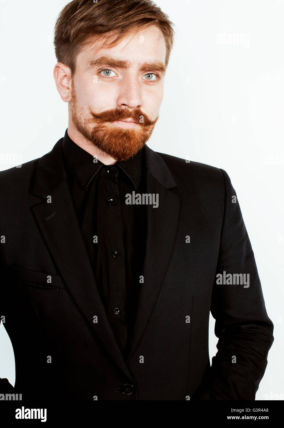 young red hair man with beard and mustache in black suit on white ...
