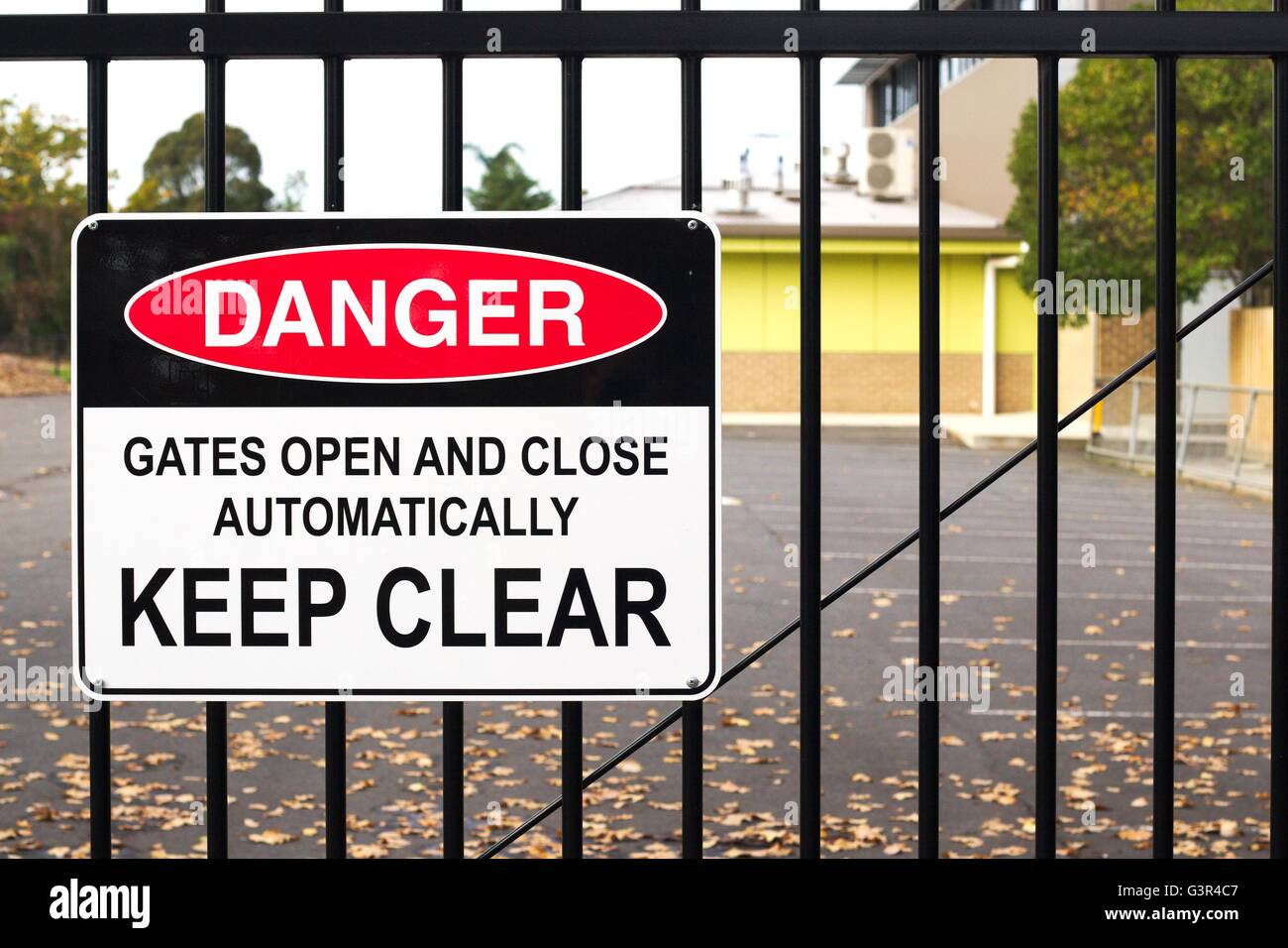 Danger sign on automatic gate outside the front of a school parking lot ...