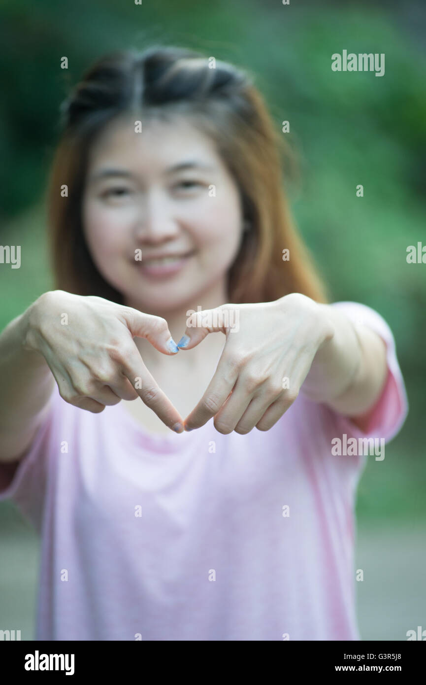 asia smiling cheerful young woman making heart sign with hands ...
