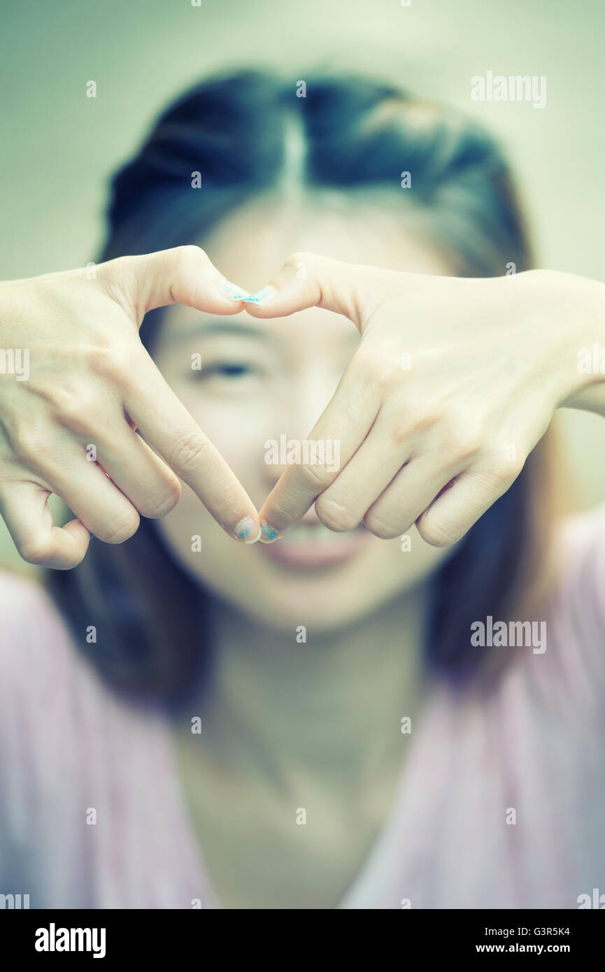 asia smiling cheerful young woman making heart sign with hands ...