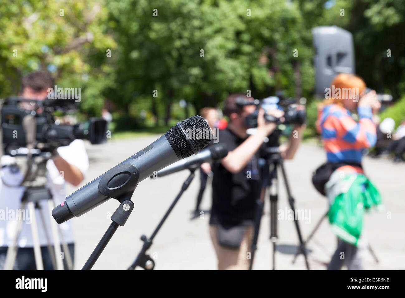 Microphone in focus against blurred camera operators and photographer ...