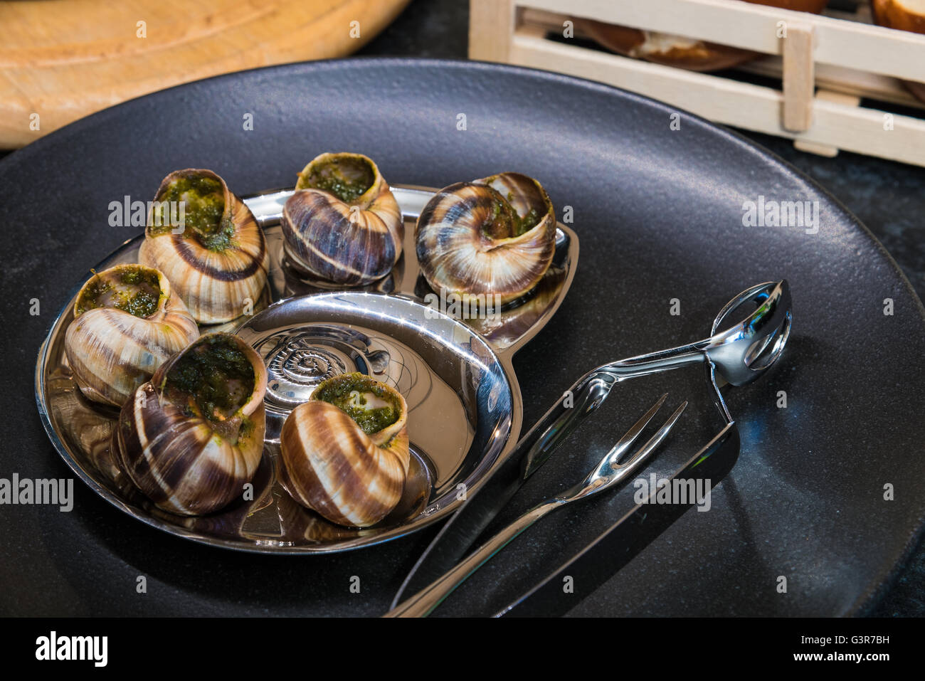 Prepared snails with garlic and parsley in black plate Stock Photo - Alamy