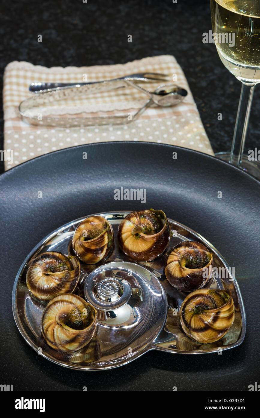 Prepared snails with garlic and parsley in black plate Stock Photo - Alamy