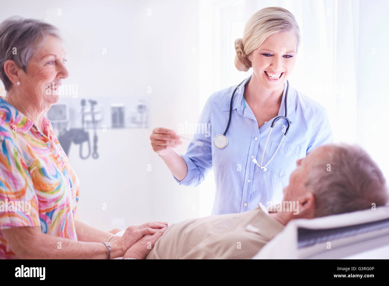 Smiling doctor checking senior man’s temperature Stock Photo - Alamy