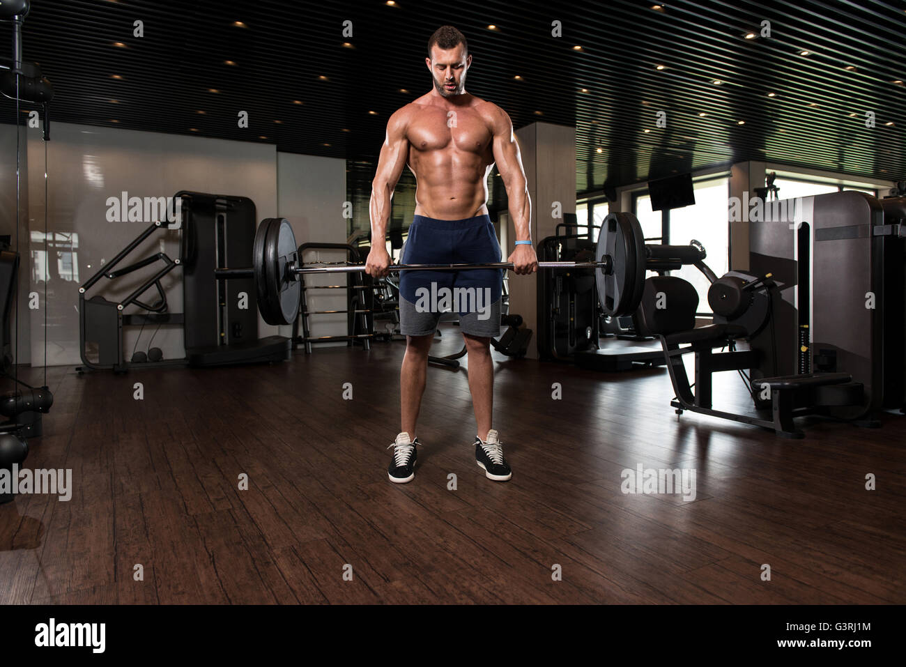 Young Bodybuilder Doing Heavy Weight Exercise For Back With Barbell In ...