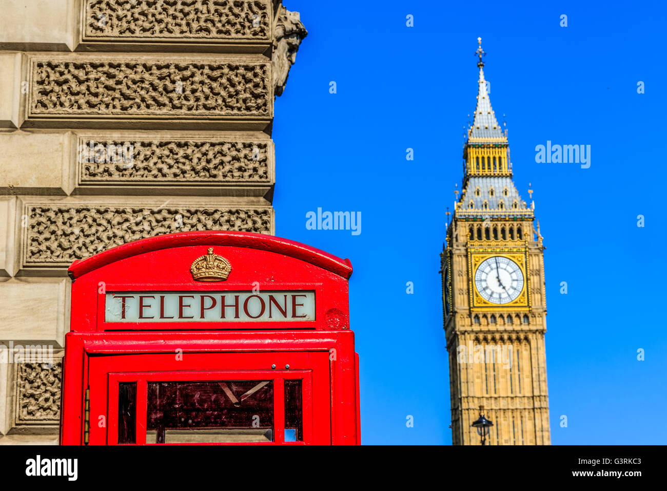 Iconic red telephone box with Big Ben against blue sky in the ...