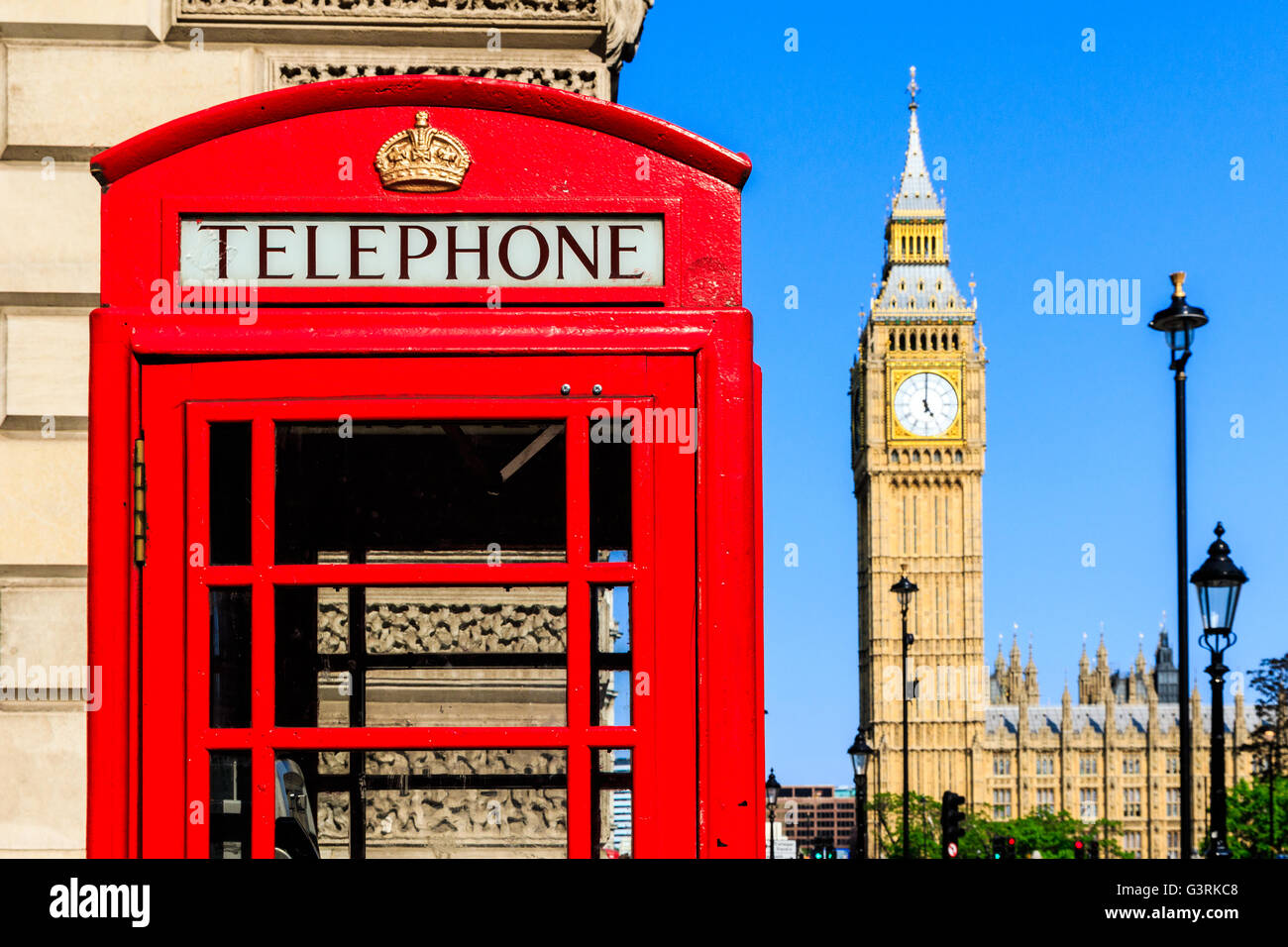 Iconic red telephone box with Big Ben and street lamps against blue sky ...