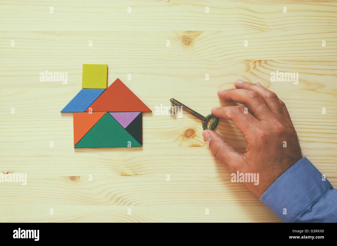 house made from tangram puzzle and key over wooden table. retro style ...