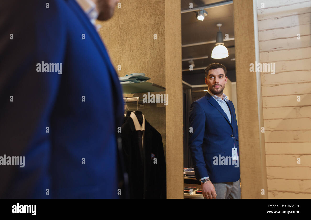 man trying jacket on at mirror in clothing store Stock Photo - Alamy