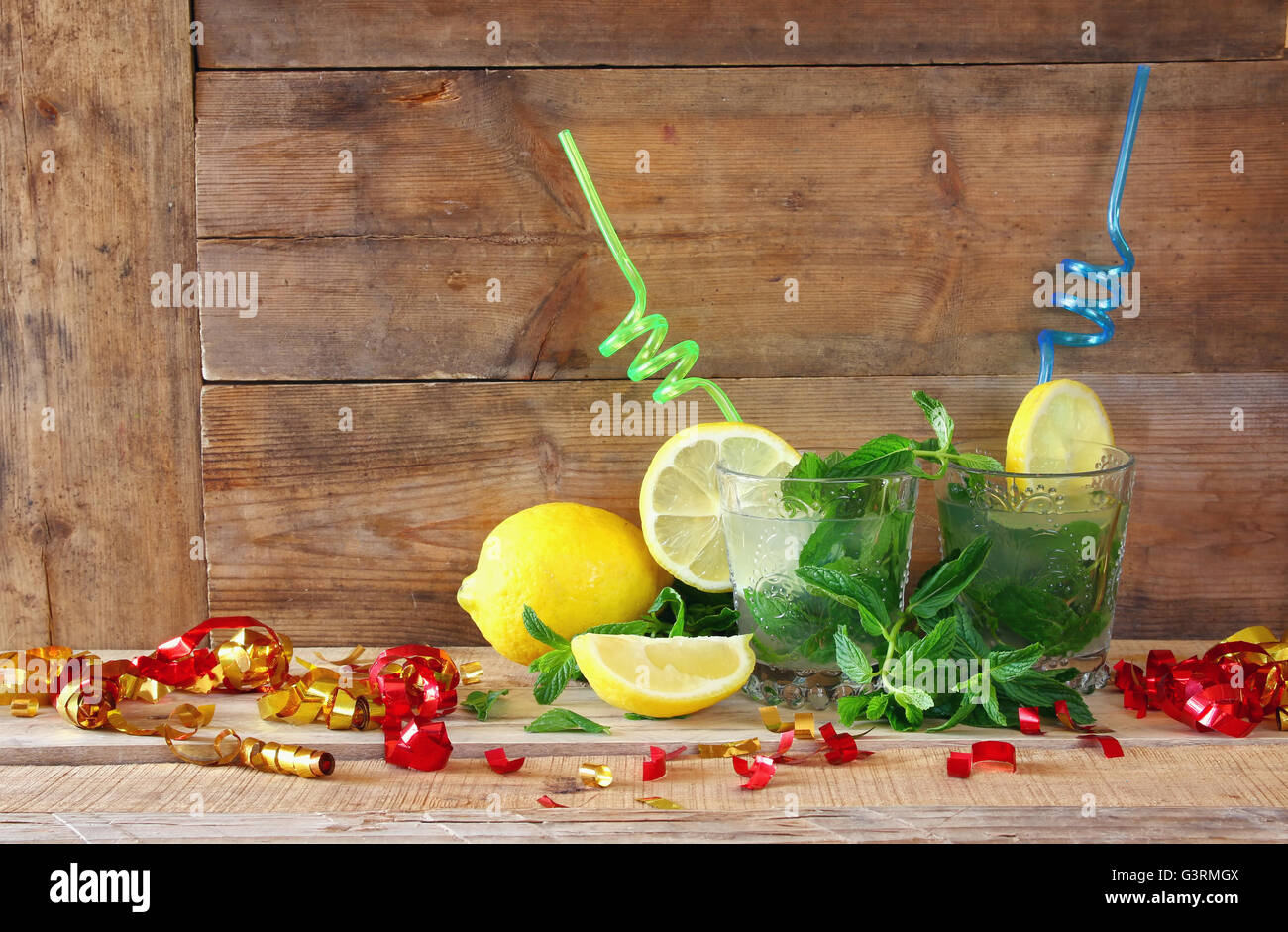 fresh mojito, party confetti and sliced lemons at the bar on a rustic ...