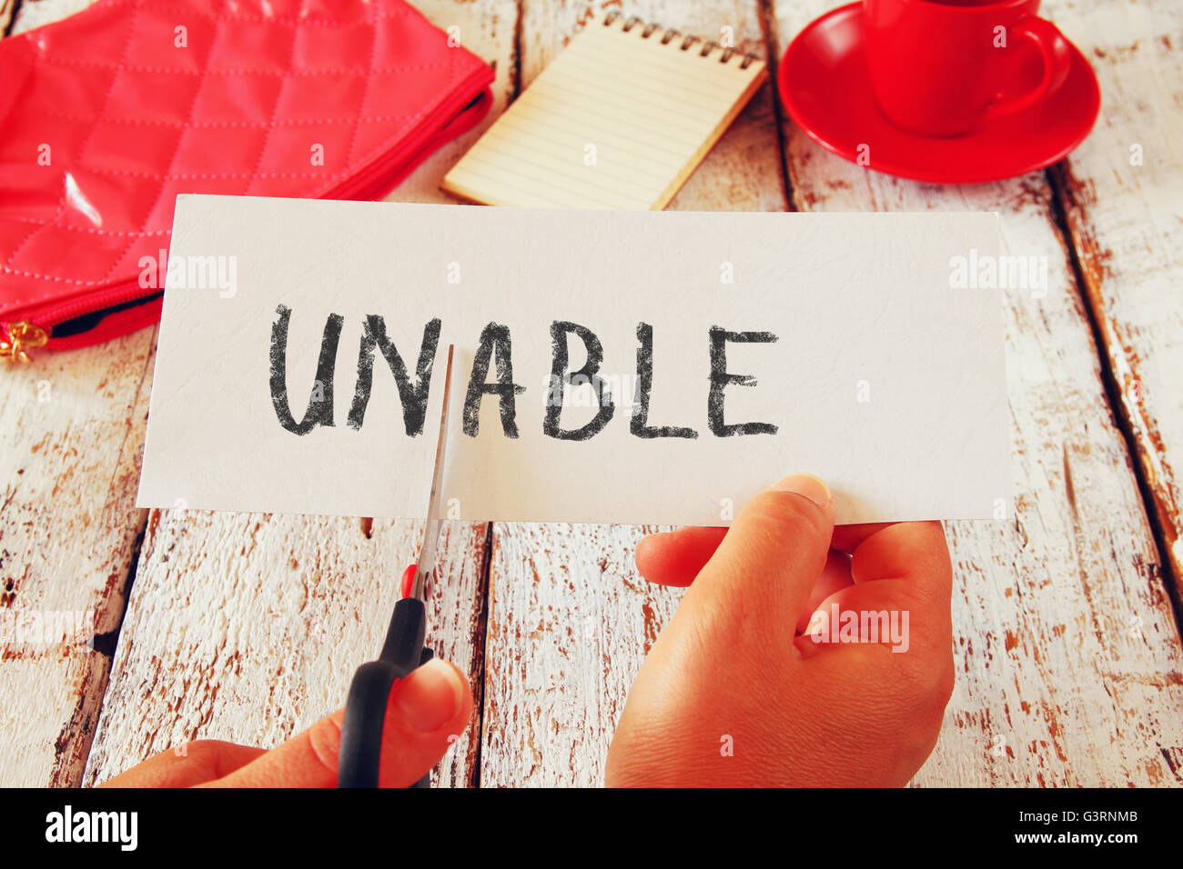 woman hand holding card with the text unable, cutting the word un so it ...