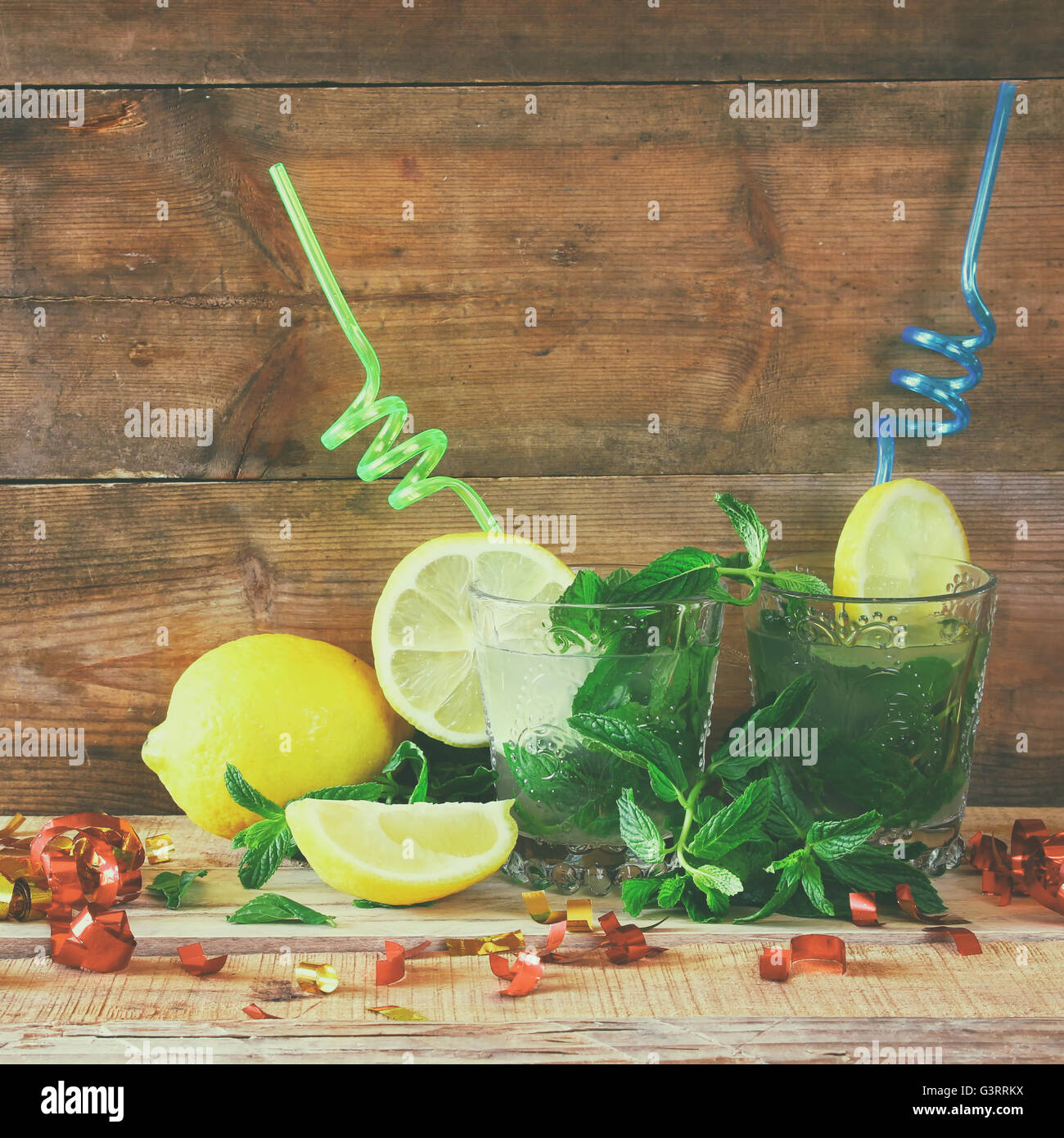fresh mojito, party confetti and sliced lemons at the bar on a rustic ...