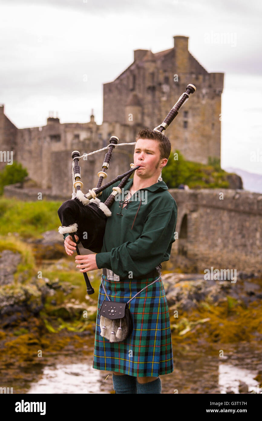 DORNIE, SCOTLAND - Bagpiper performs in front of Eilean Donan Castle at ...