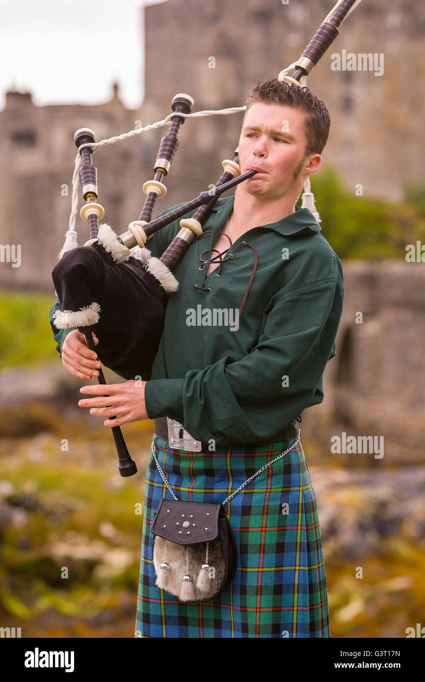 DORNIE, SCOTLAND - Bagpiper performs in front of Eilean Donan Castle at ...