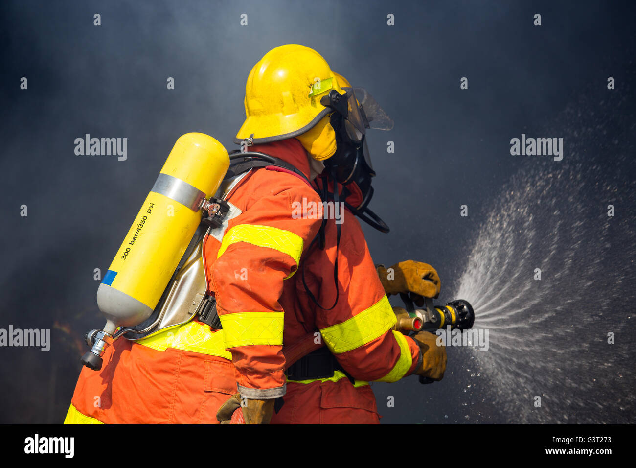 2 firemen use hydrant nozzle fighting with fire surround with dark ...