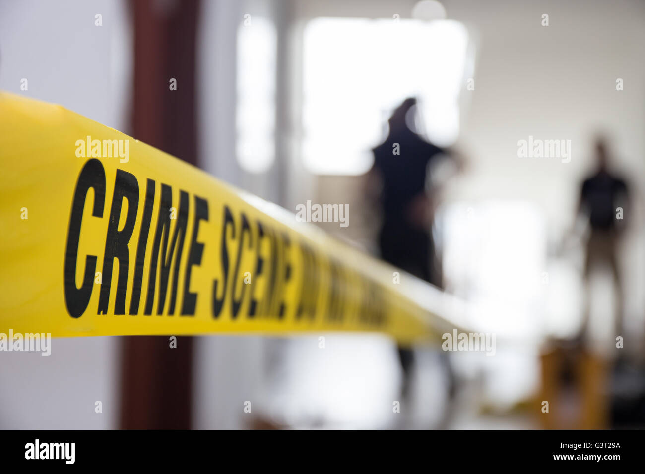 crime scene tape in building with blurred forensic team background ...