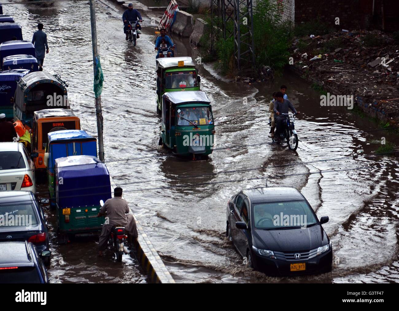 Peshawar. 15th June, 2016. Vehicles move into flooded water after heavy ...