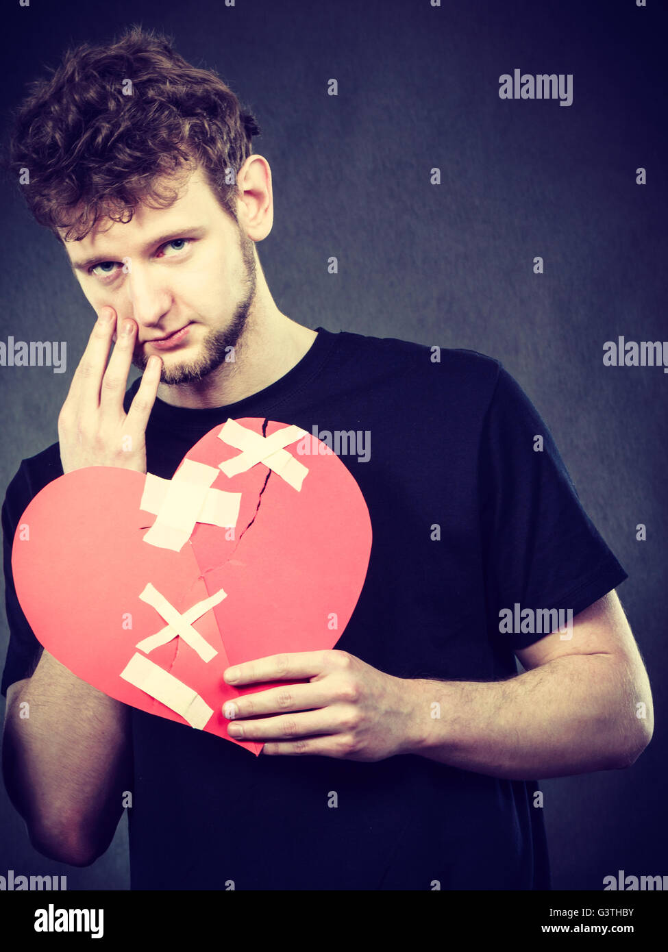 Heart broken concept. Unhappy sad man guy holding glued on love sign ...